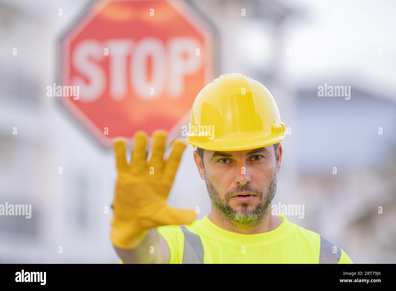 Builder showing STOP. Serious builder with stop road sign. Builder with ...