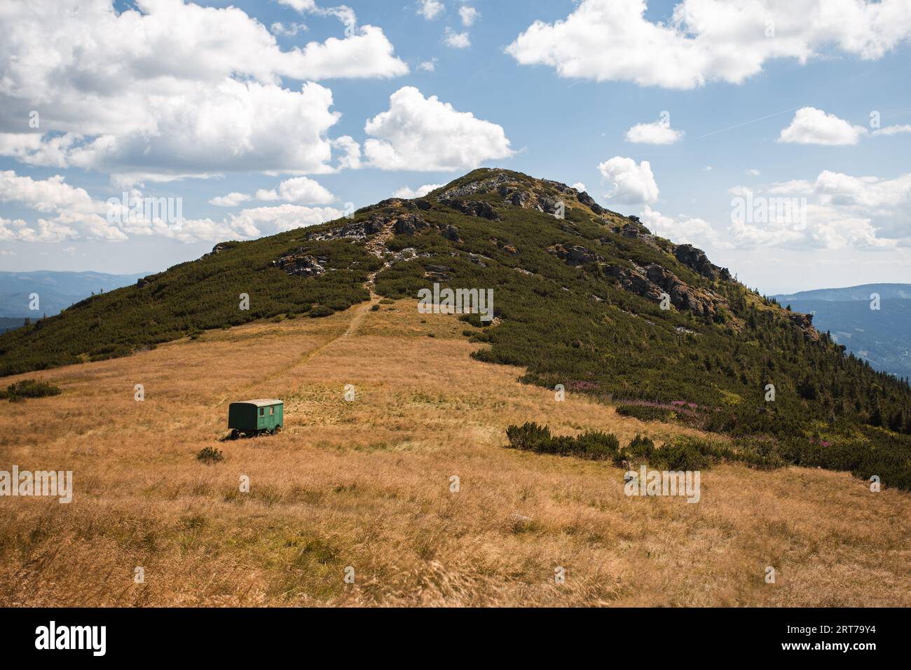 Ridge of the mountain and dry meadow with green caravan under the hill ...
