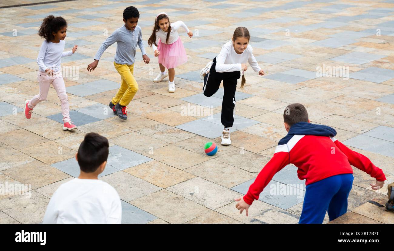 Cheerful tween schoolchildren playing with ball near school Stock Photo ...