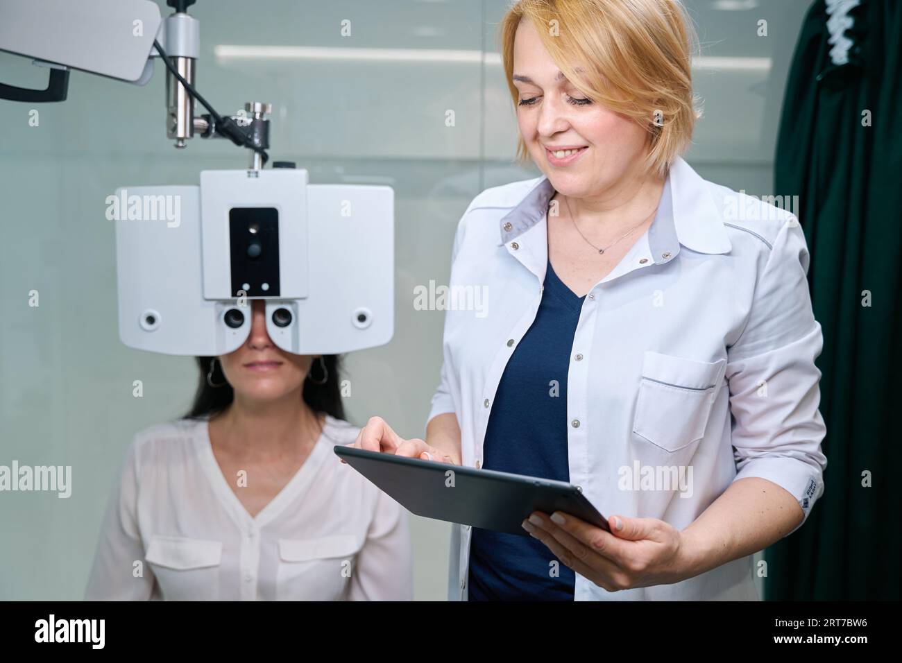 Adult female taking digital refraction test supervised by eye doctor ...