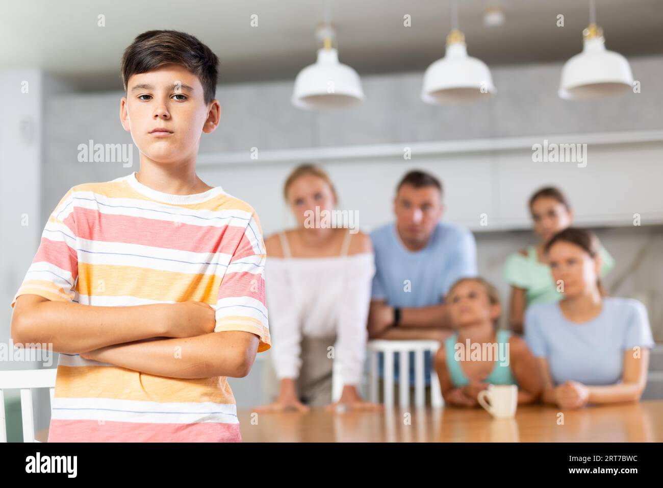 Angry male child turned away from parents and sisters and ignores ...