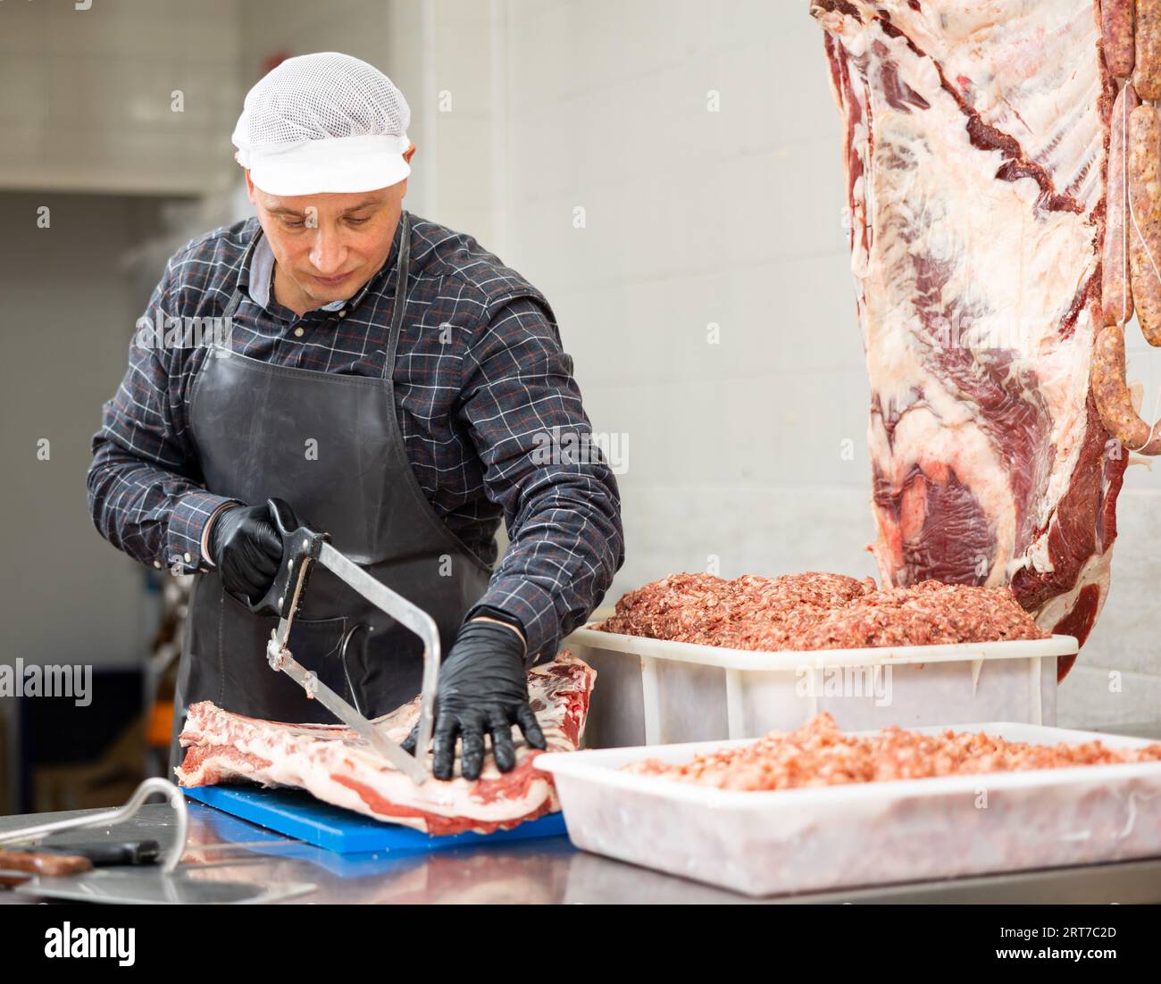 Adult male butcher sawing beef ribs Stock Photo - Alamy