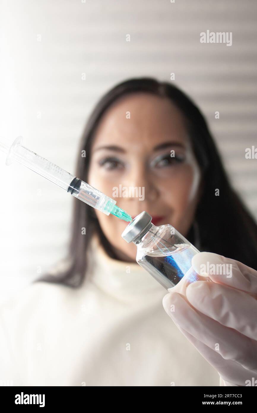 Woman doctor showing new syringe needle and vial first injection bottle ...