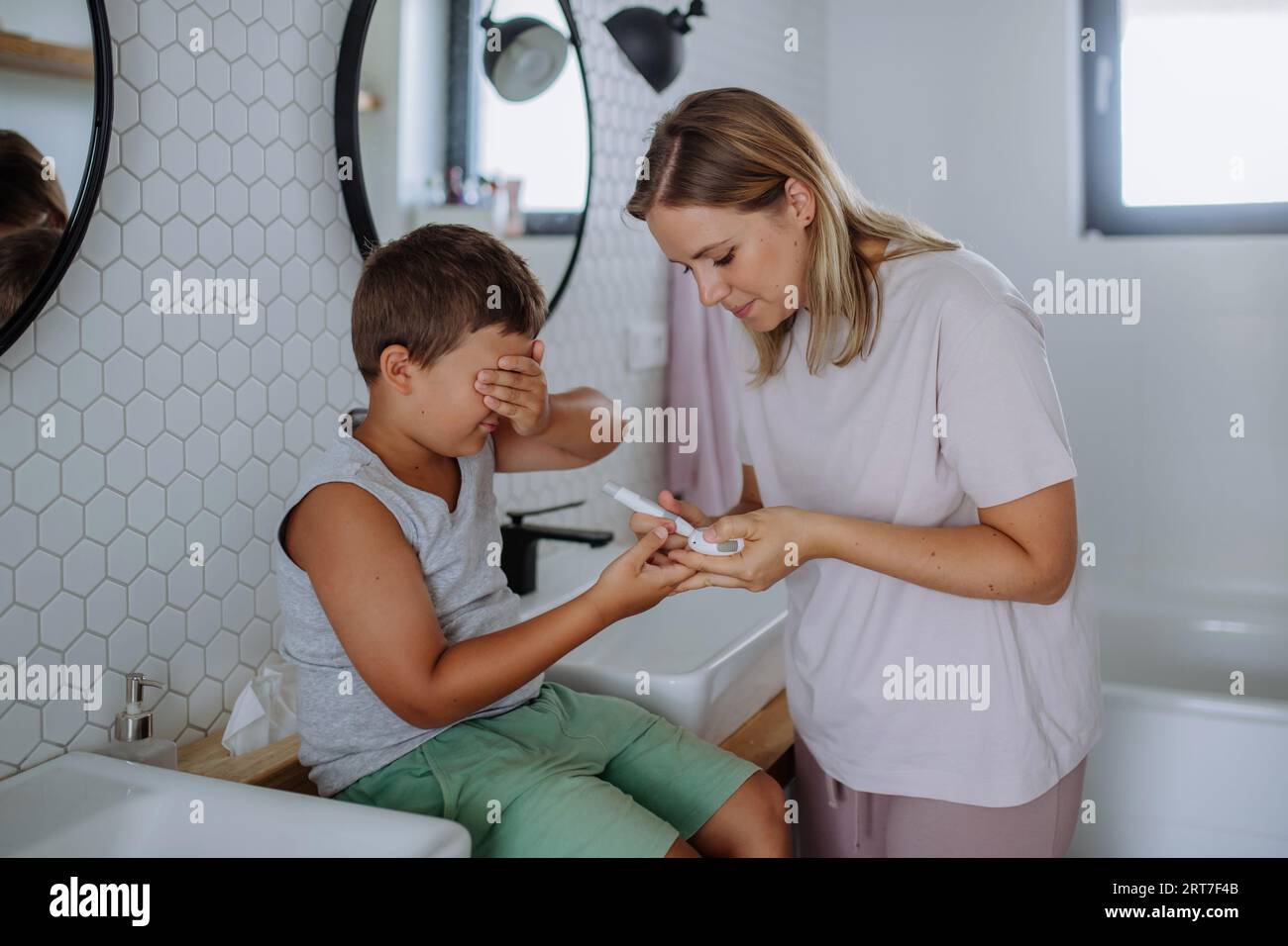 Mother checking her son's blood glucose level at home using a ...