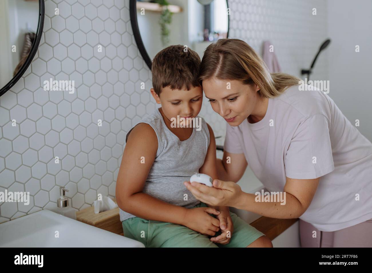 Mother checking her son's blood glucose level at home using a ...