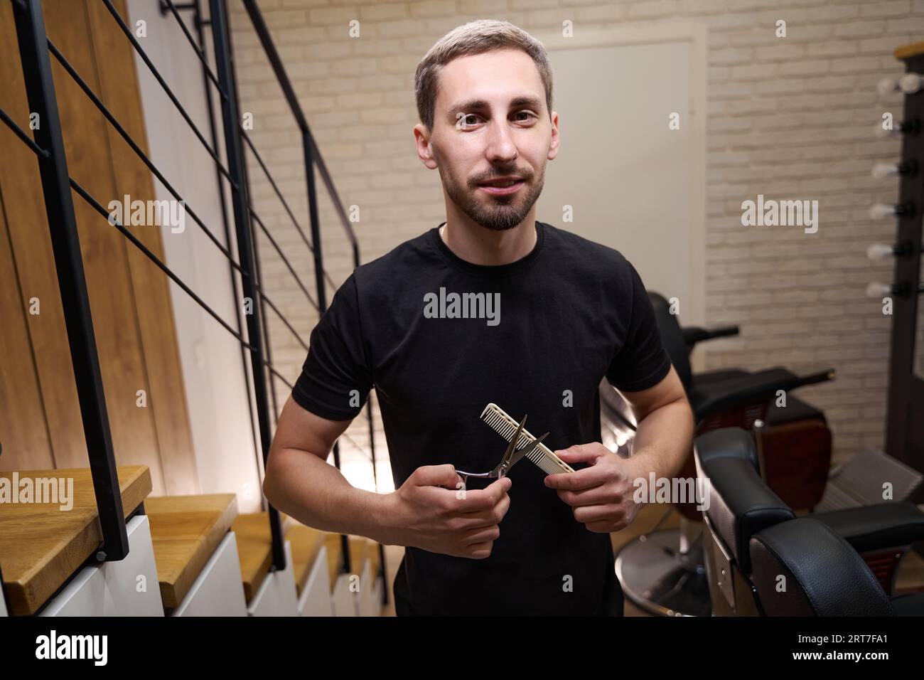 Handsome male barber holding scissors and comb in hands Stock Photo - Alamy