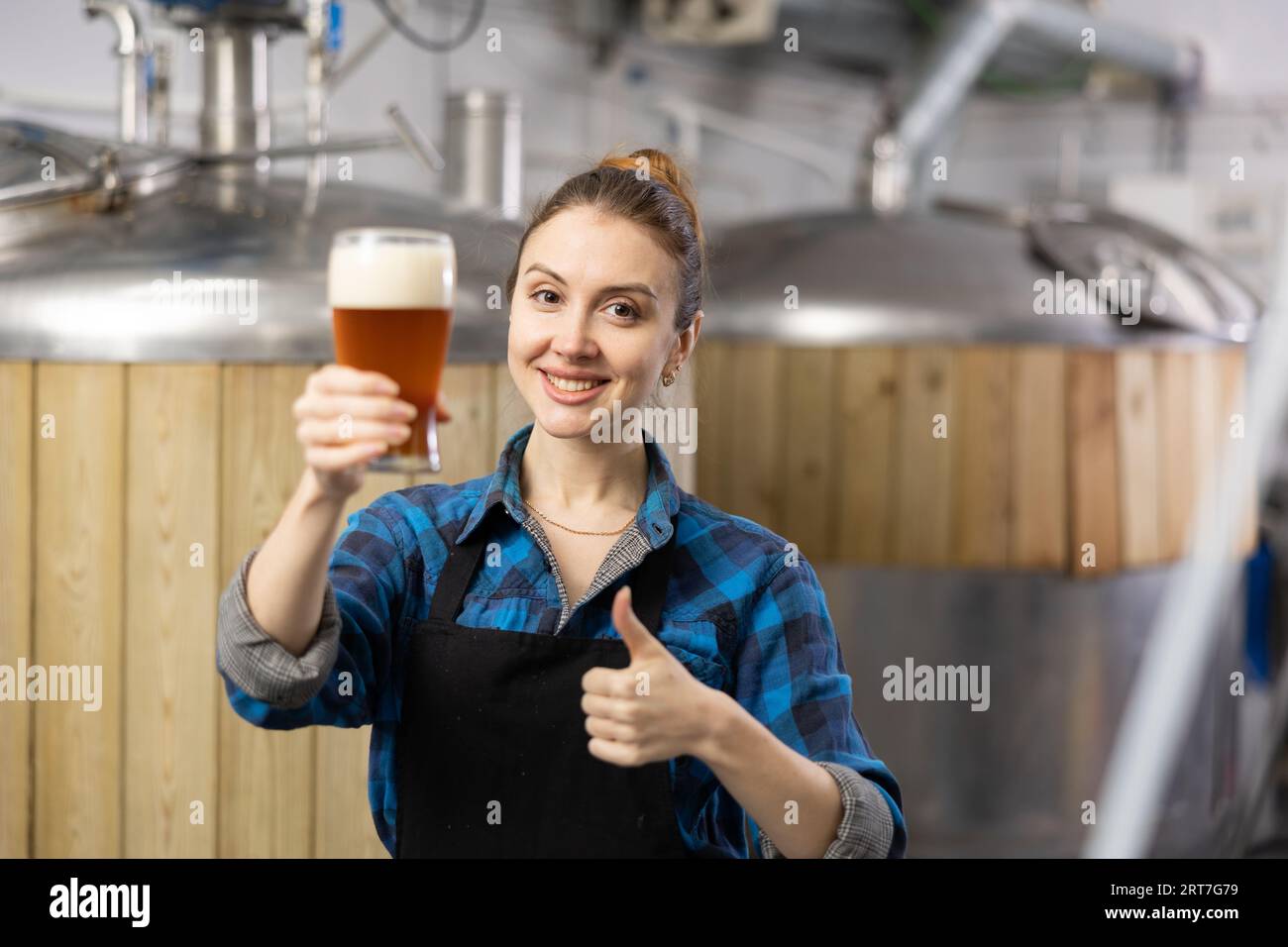 Female brewer showing thumbs up while holding glass of beer Stock Photo ...