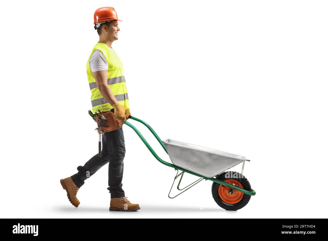 Full length profile shot of a construction worker pushing a wheelbarrow ...
