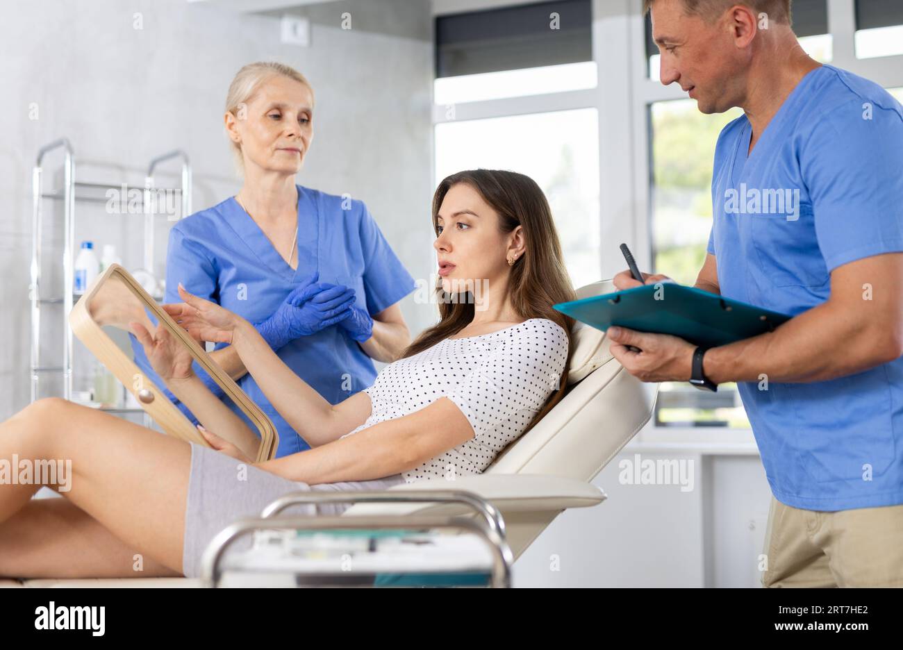 Elderly lady dermatologist examines skin of womans face, male nurse ...