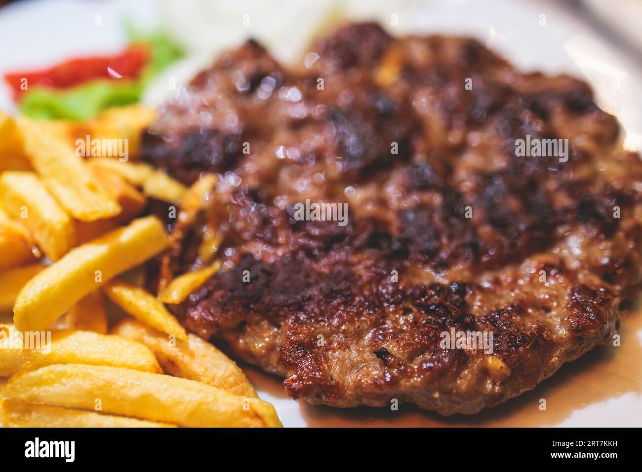 Pljeskavica with french fries on a plate, traditional serbian dish ...