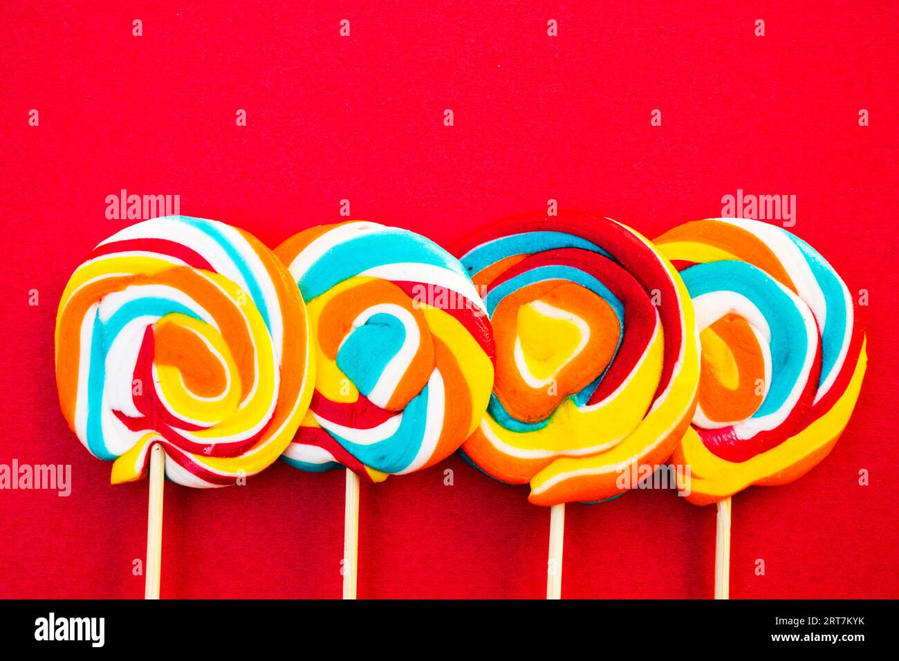 Colorful spiral lollipop candy on stick. On a red background Stock ...