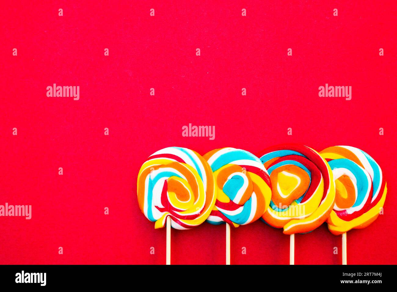 Colorful spiral lollipop candy on stick. On a red background Stock ...