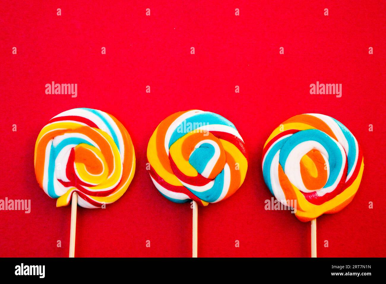Colorful spiral lollipop candy on stick. On a red background Stock ...