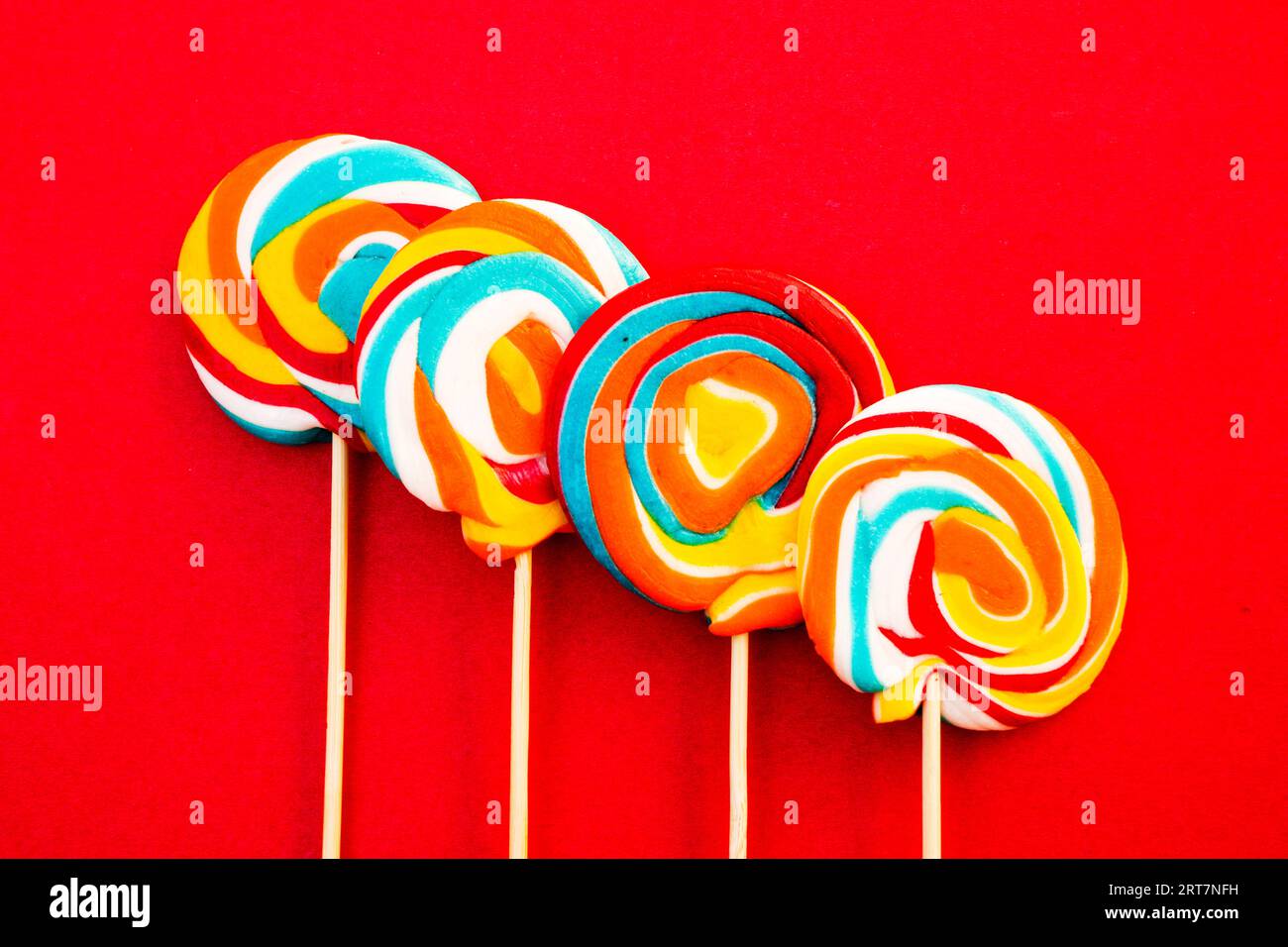 Colorful spiral lollipop candy on stick. On a red background Stock ...