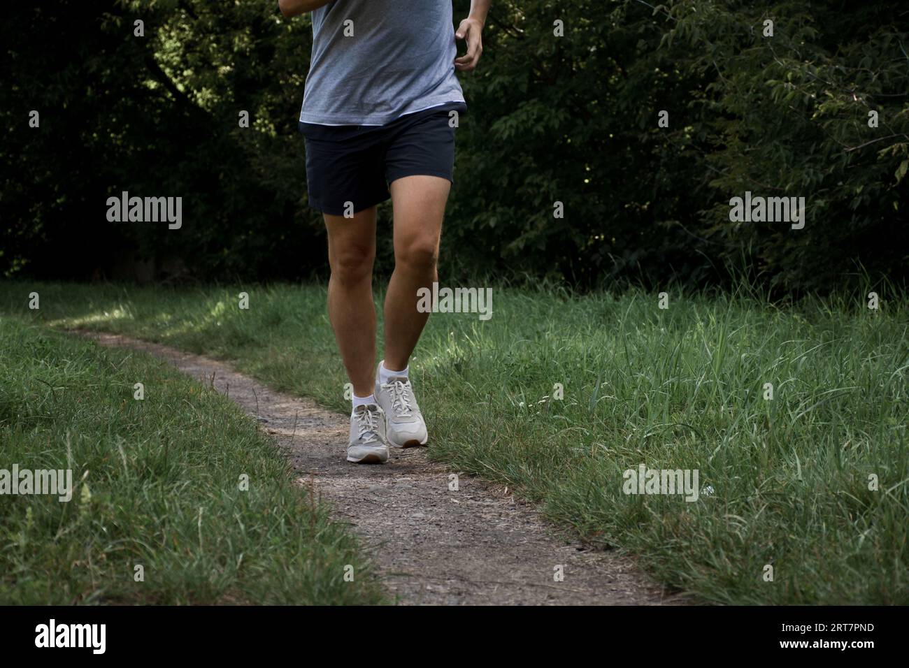 men's slender pumped up legs run along the path in the park on a warm ...