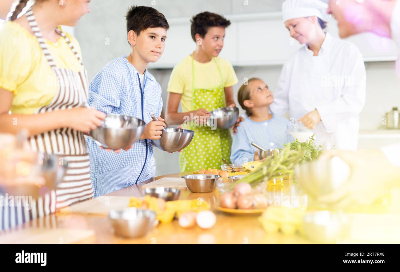 Interested boy listening to advice of professional chef during cooking ...