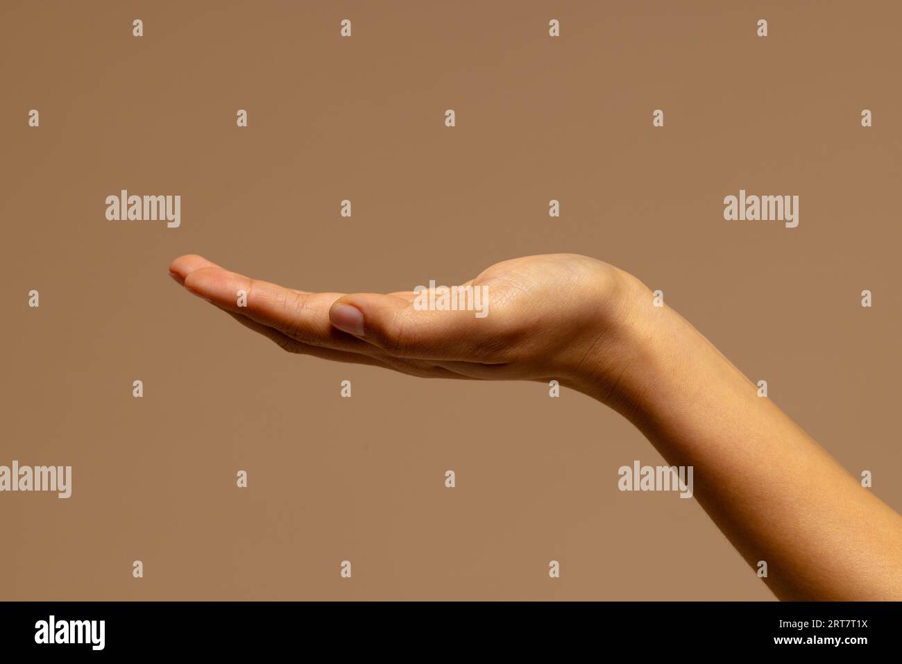 Upturned hand of biracial woman on brown background with copy space ...