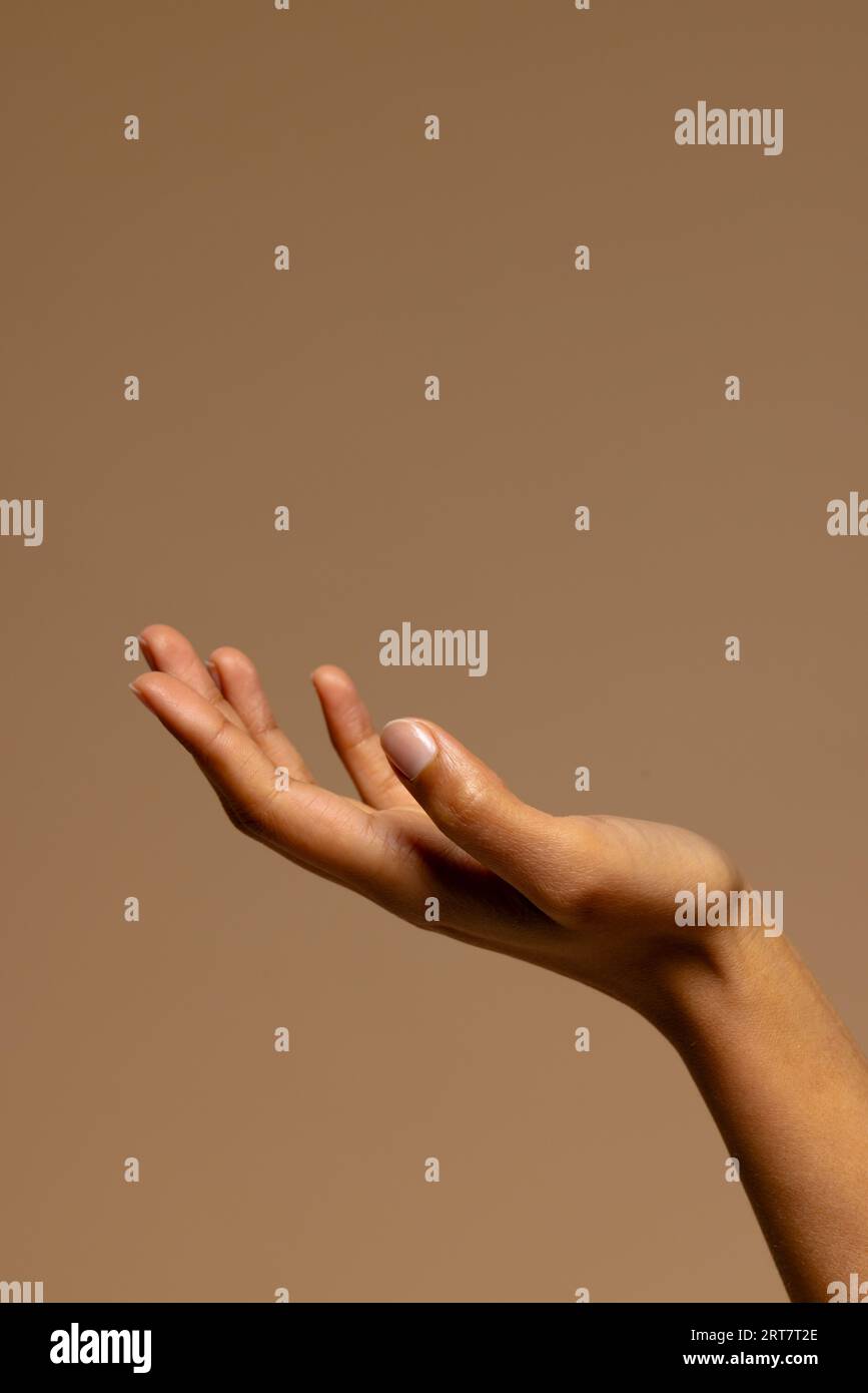 Upturned hand of biracial woman on brown background with copy space ...
