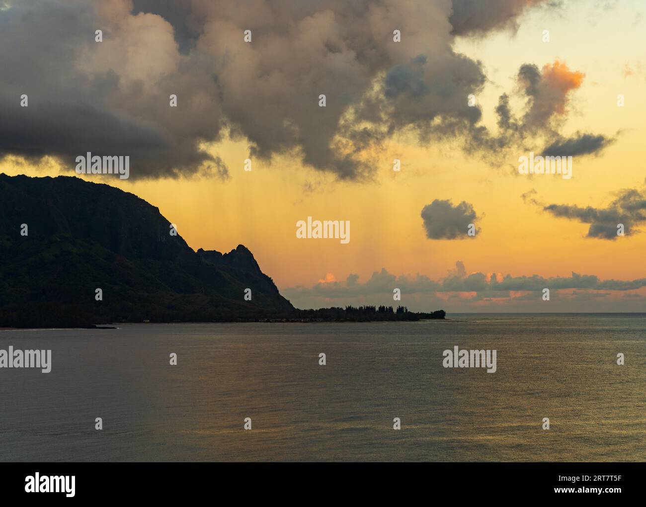 Rising sun illuminates rain clouds over the mountain peaks of Na Pali ...
