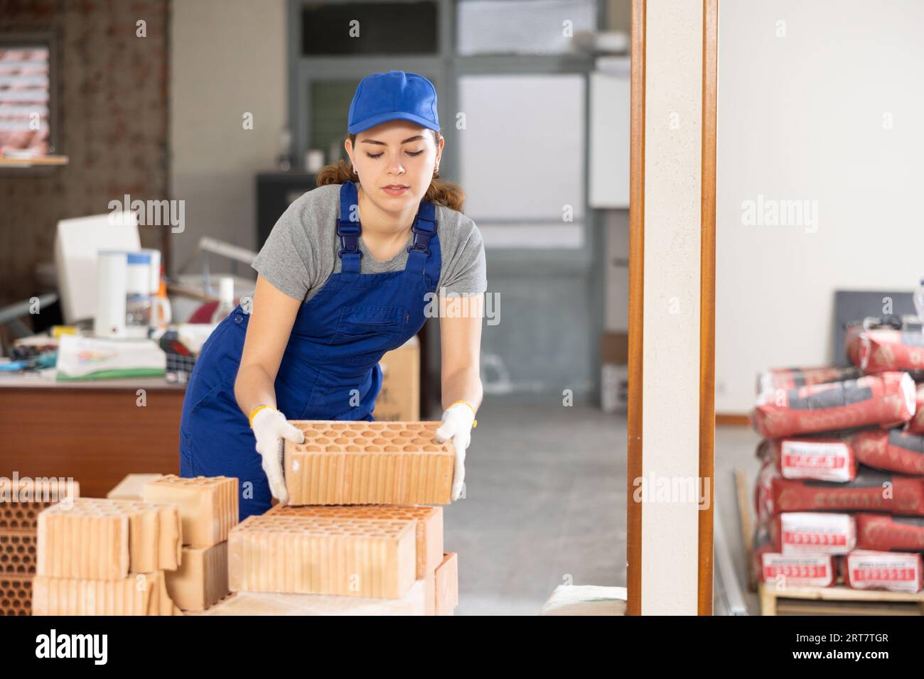 Young woman builder stacking bricks in building site Stock Photo - Alamy