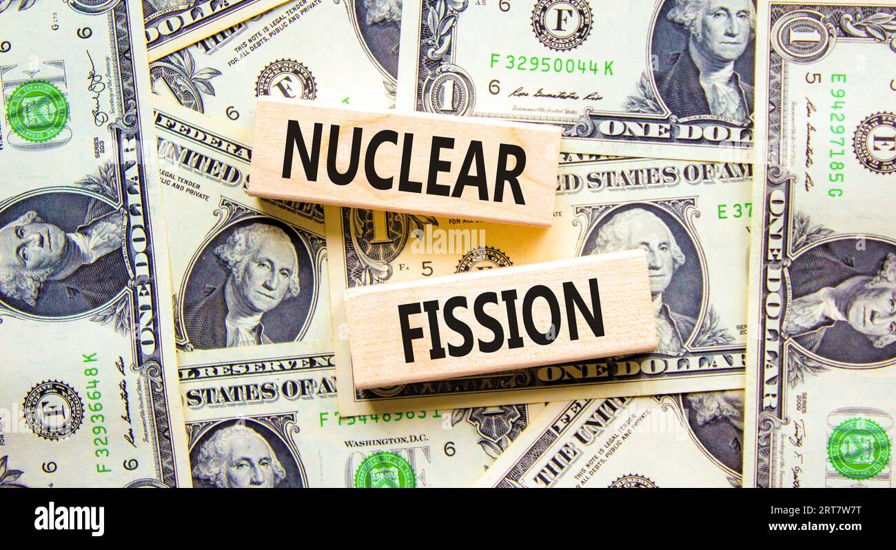 Nuclear fission symbol. Concept words Nuclear fission on beautiful wooden blocks. Dollar bills ...