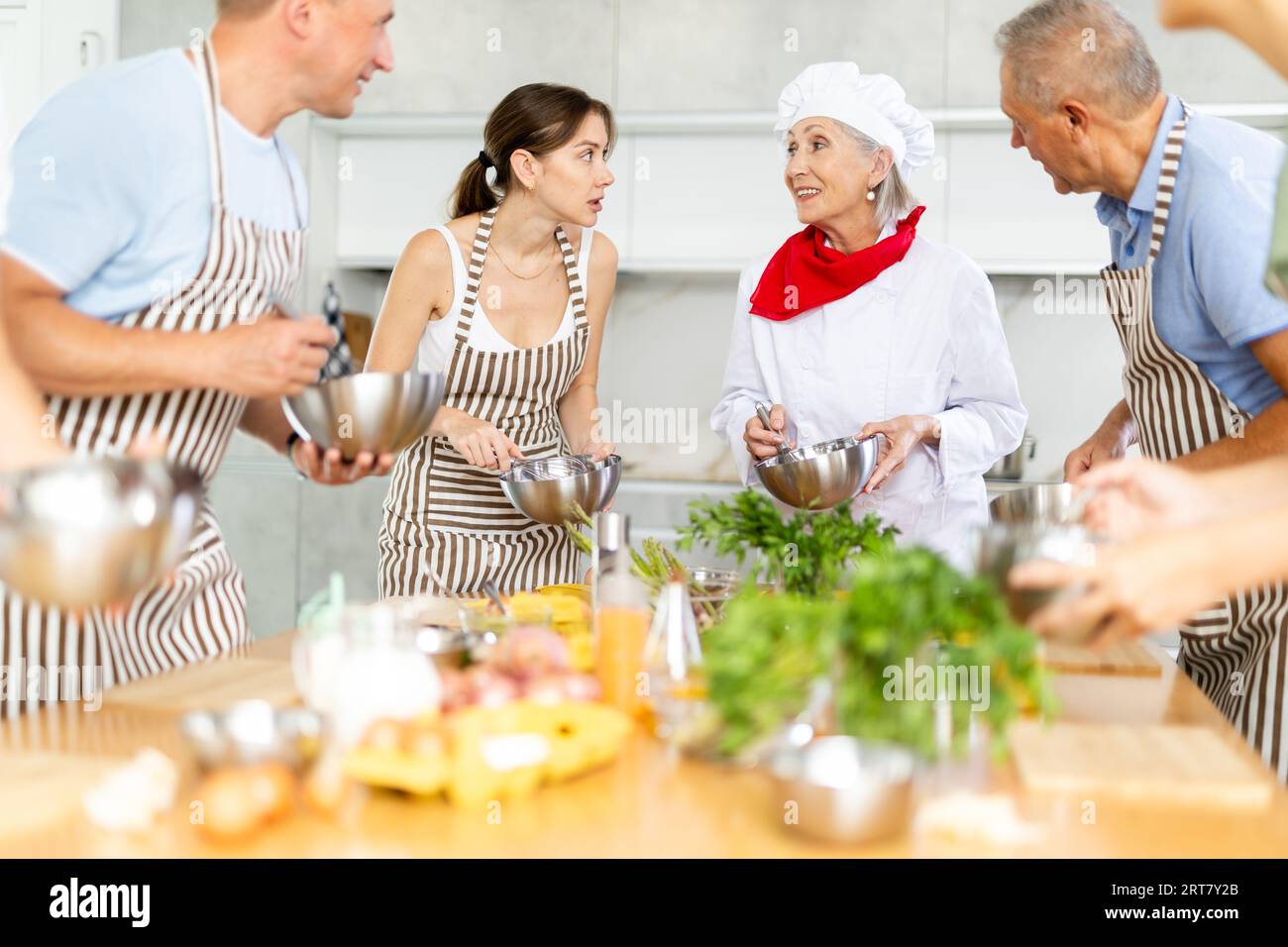 Senior female chef giving culinary classes to group of people Stock ...