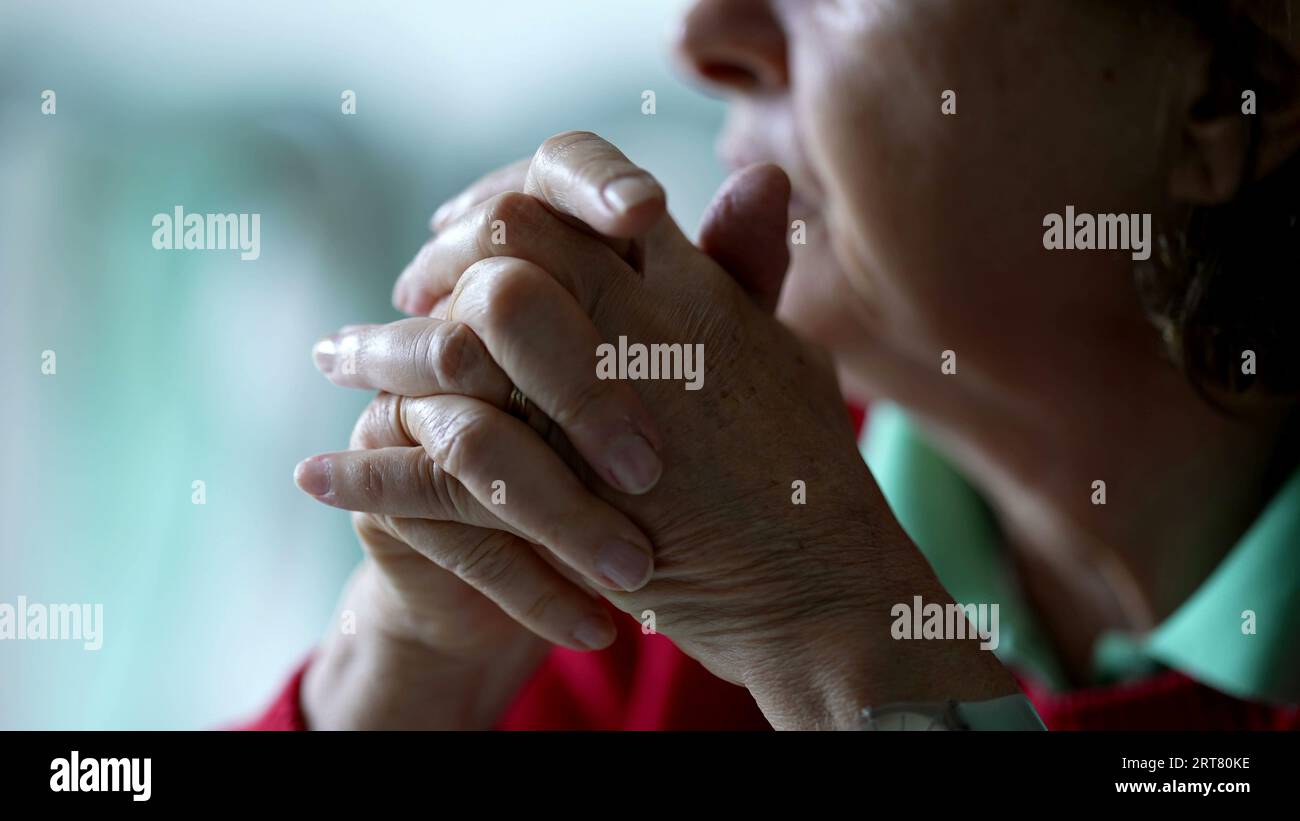 Close-up senior hands clenched in contemplation. Pensive body language ...