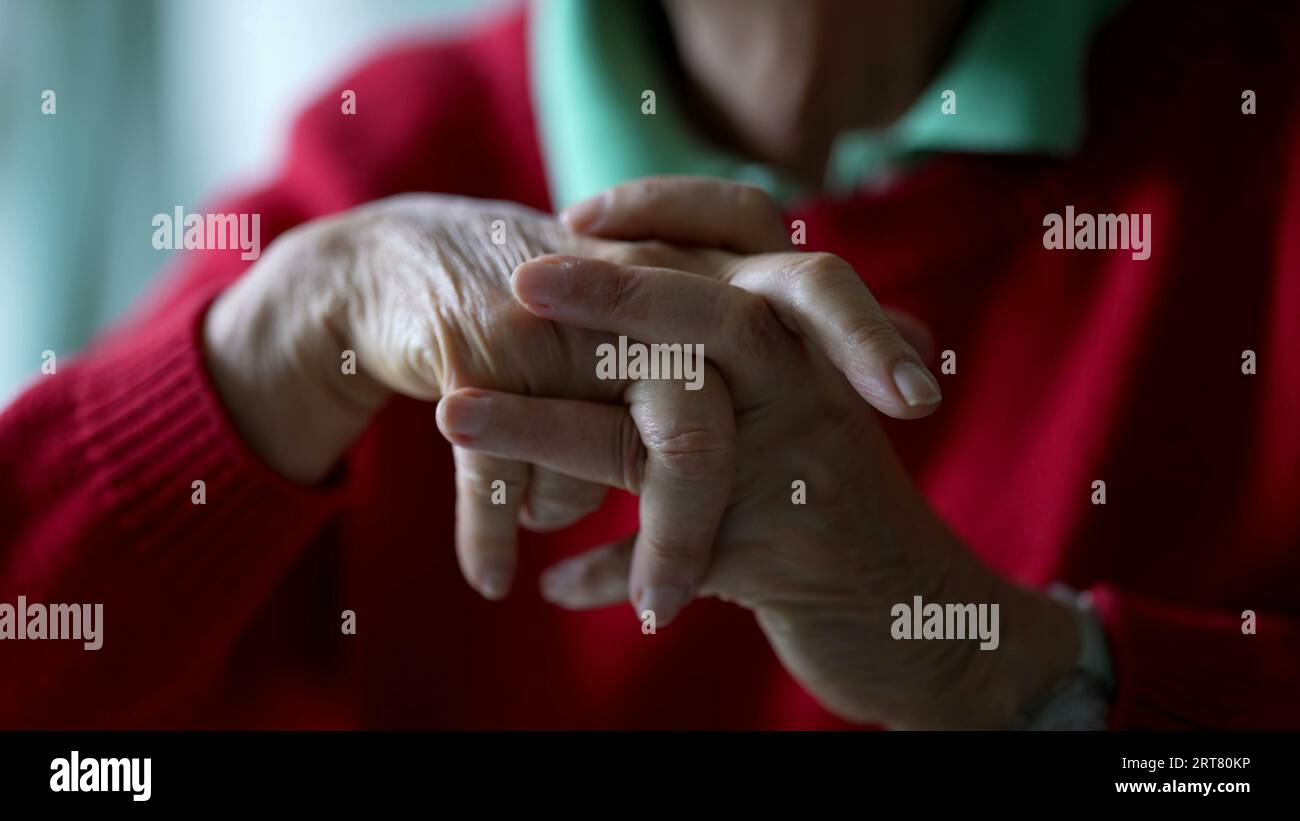 Close-up senior hands clenched in contemplation. Pensive body language ...