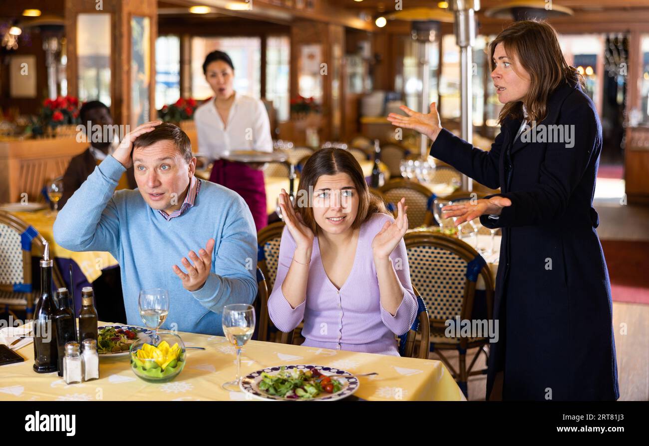 Resentful wife scolding her husband spending time with another woman at ...