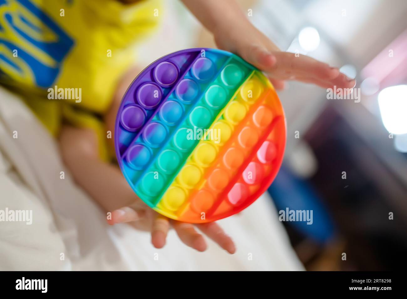 hands of toddler child are holding round pop it. A cheerful child on ...