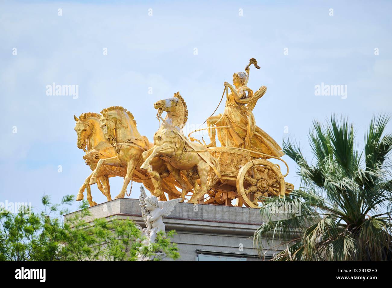 Golden sculpture of a chariot driver with three horses pulling the ...