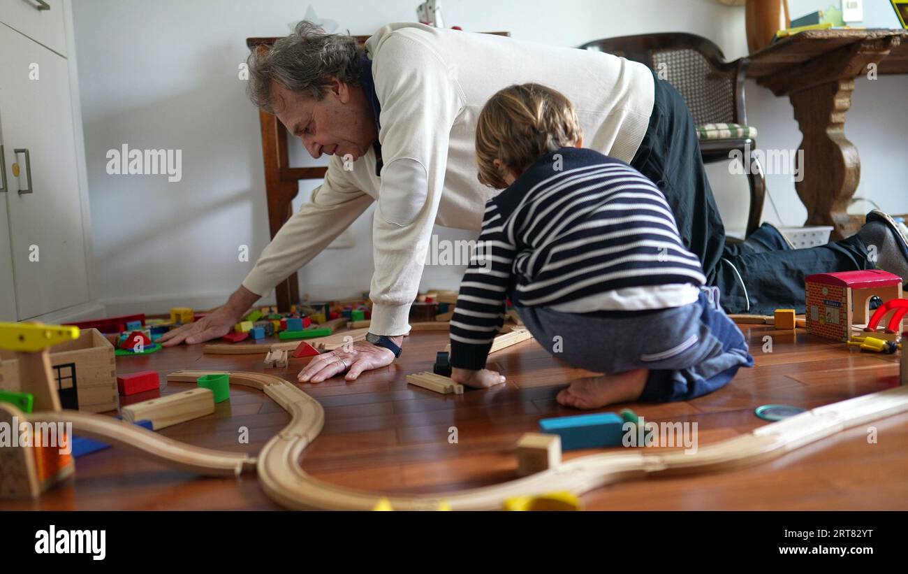 Grandfather and Grandson Constructing Train Tracks on Hardwood Floor ...