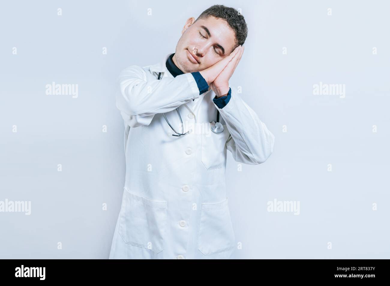 Young doctor making sleep gesture isolated. Handsome doctor making ...