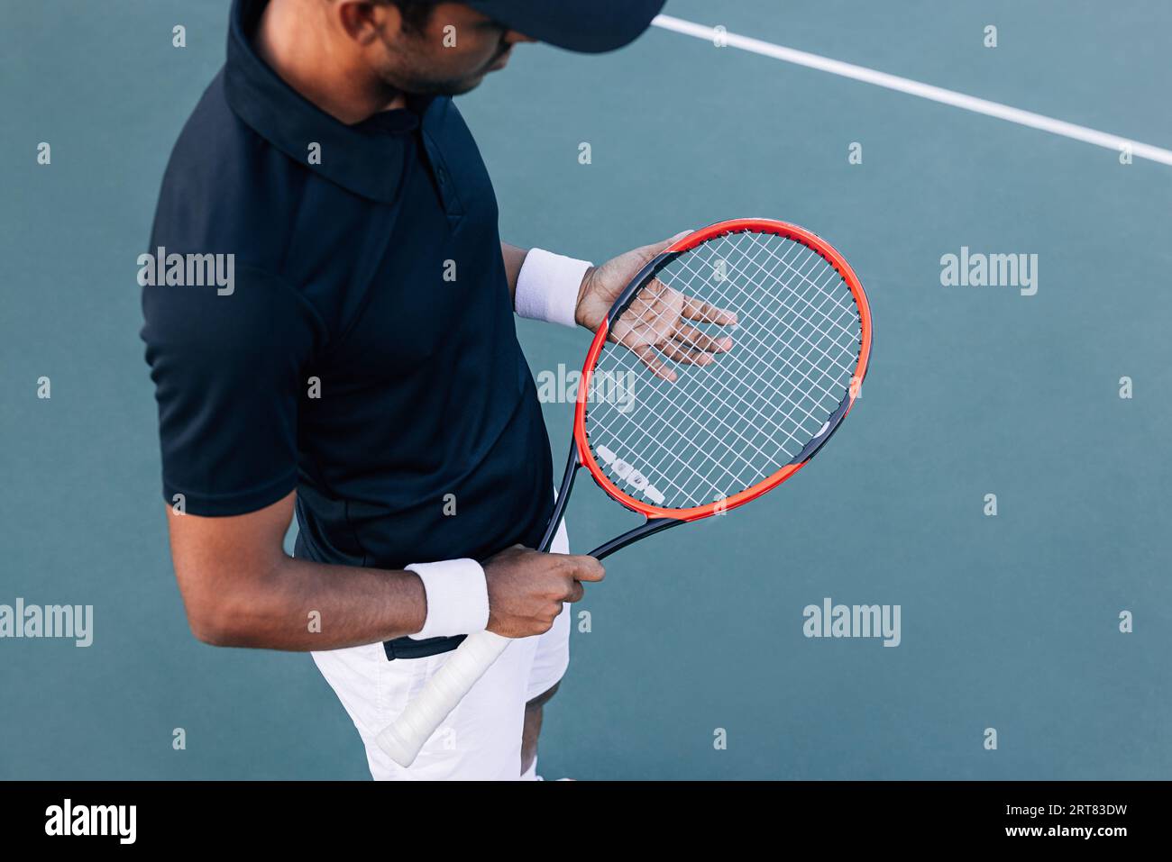 High angle of an unrecognizable male adjusting his tennis racket Stock ...