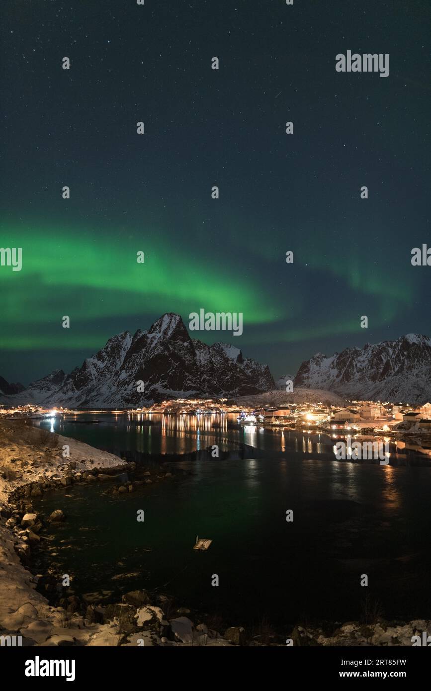 Dancing green polar lights over the village Reine on the Lofoten islands in Norway at night in ...