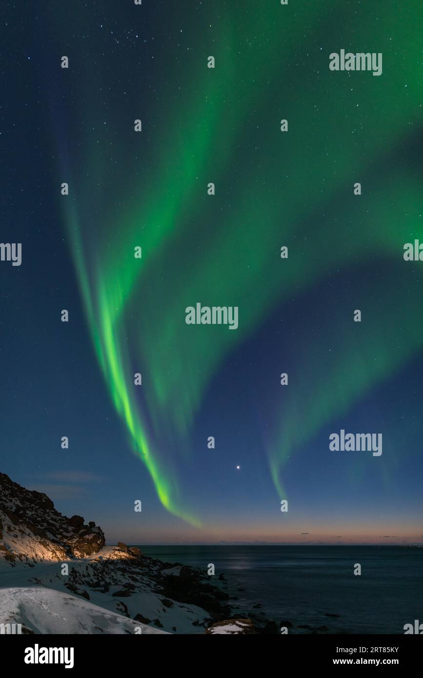 Spectacular dancing green strong northern lights over the famous round boulder beach near ...