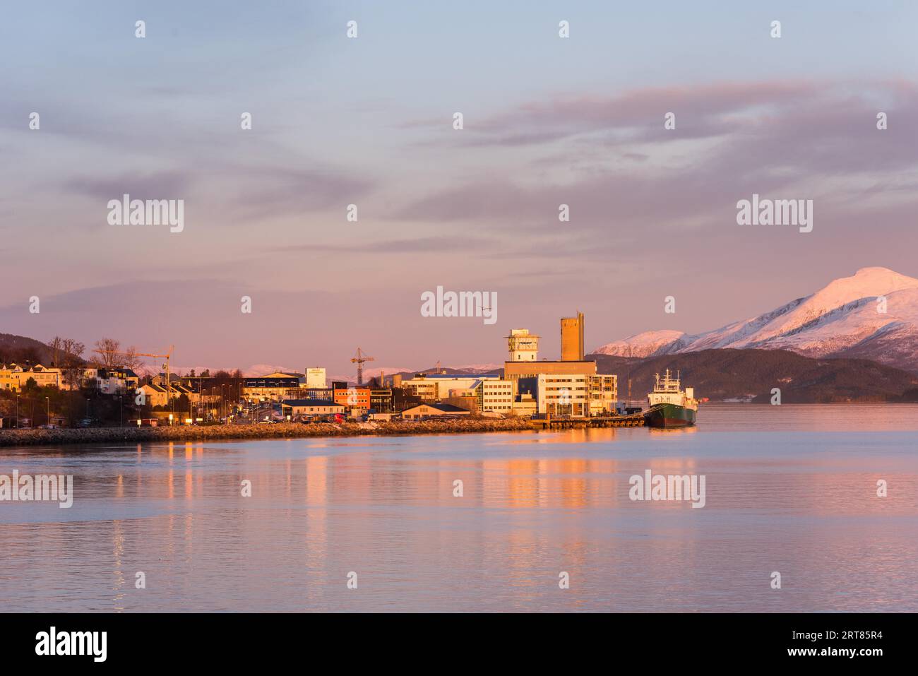 The port of the town Molde in Norway in golden evening light with snow ...