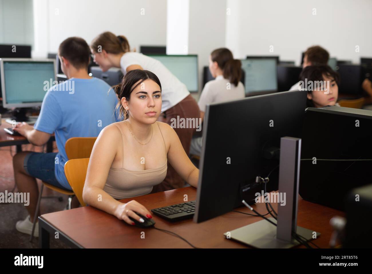 Smart Latin female teenager learning computer science while she is ...