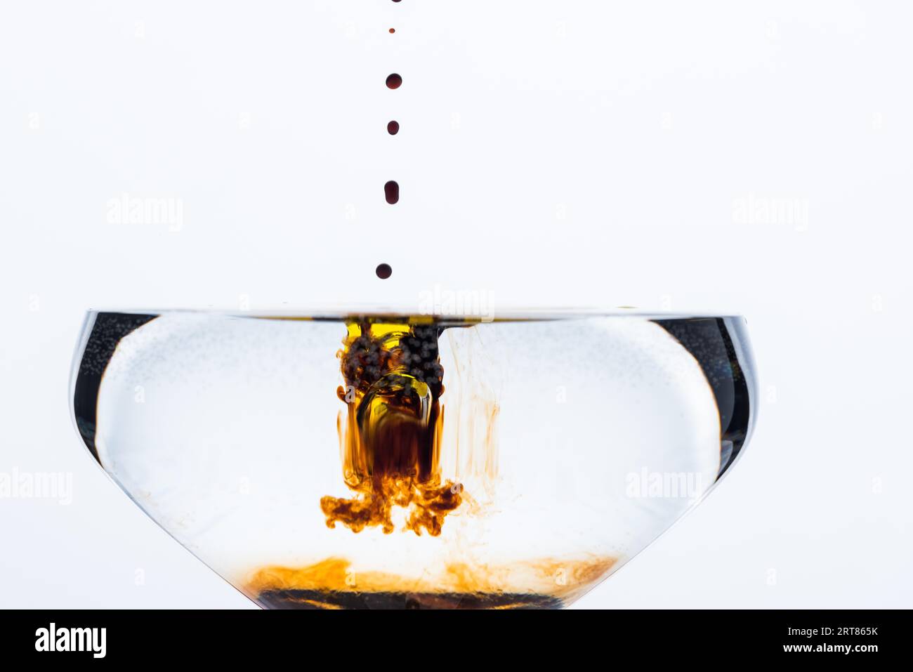 Detail of drops of dark brown balsamico vinegar dripping into glass of ...