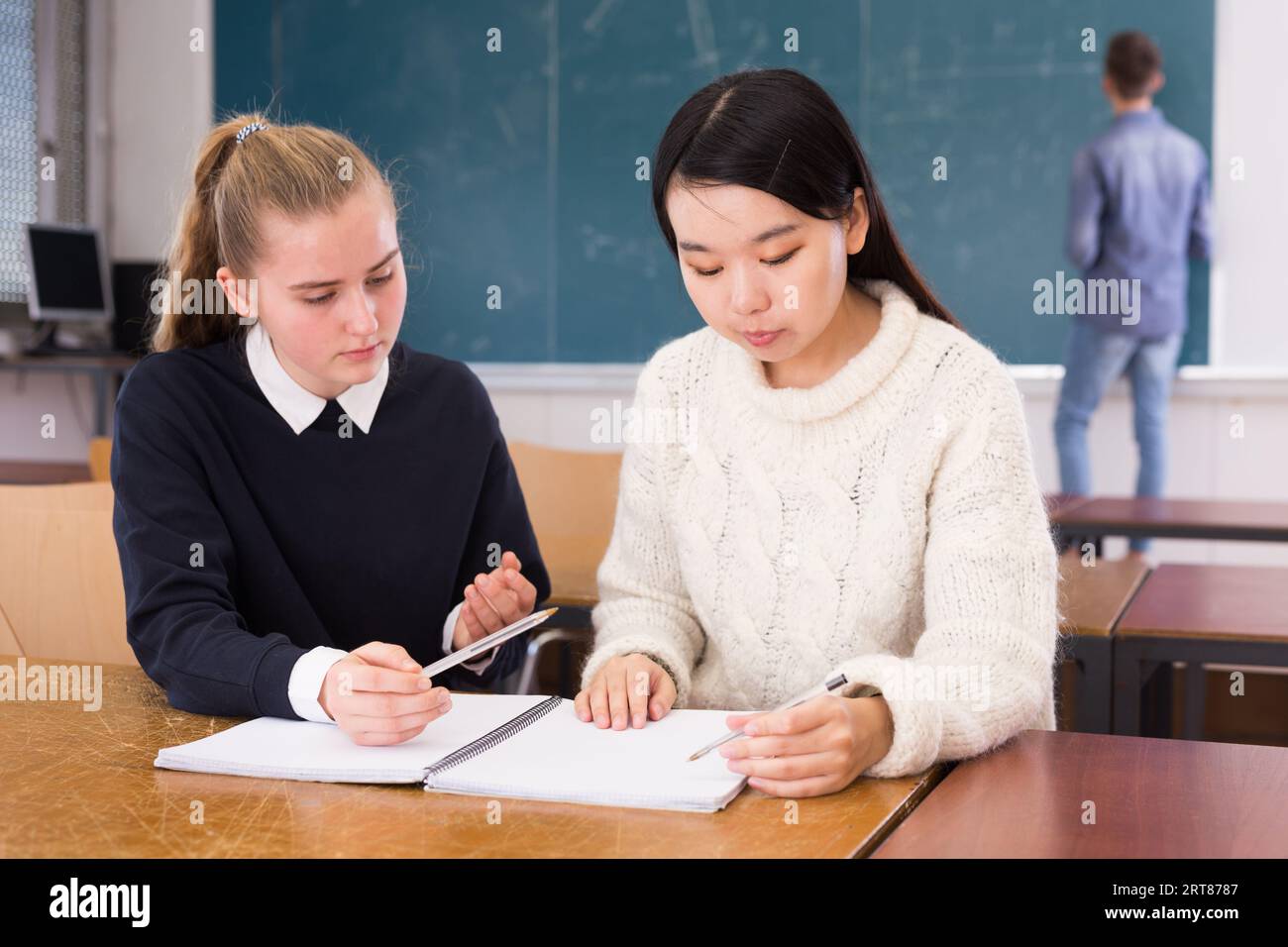 Tired female students during writing notes in classroom Stock Photo - Alamy