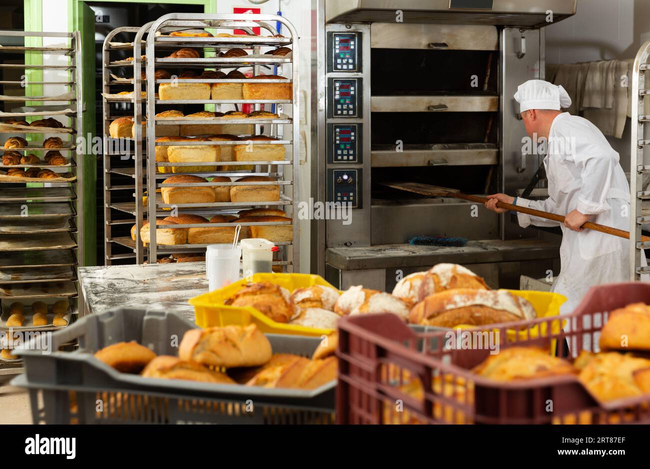 Baker taking out bread from oven Stock Photo - Alamy