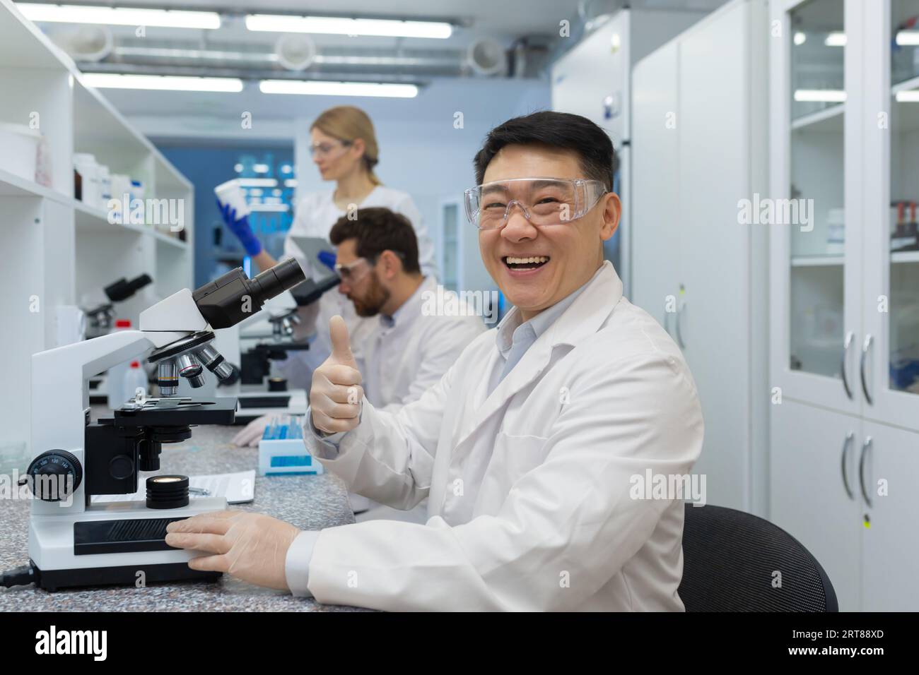 Portrait of a smiling and a young Asian male doctor, scientist sitting ...