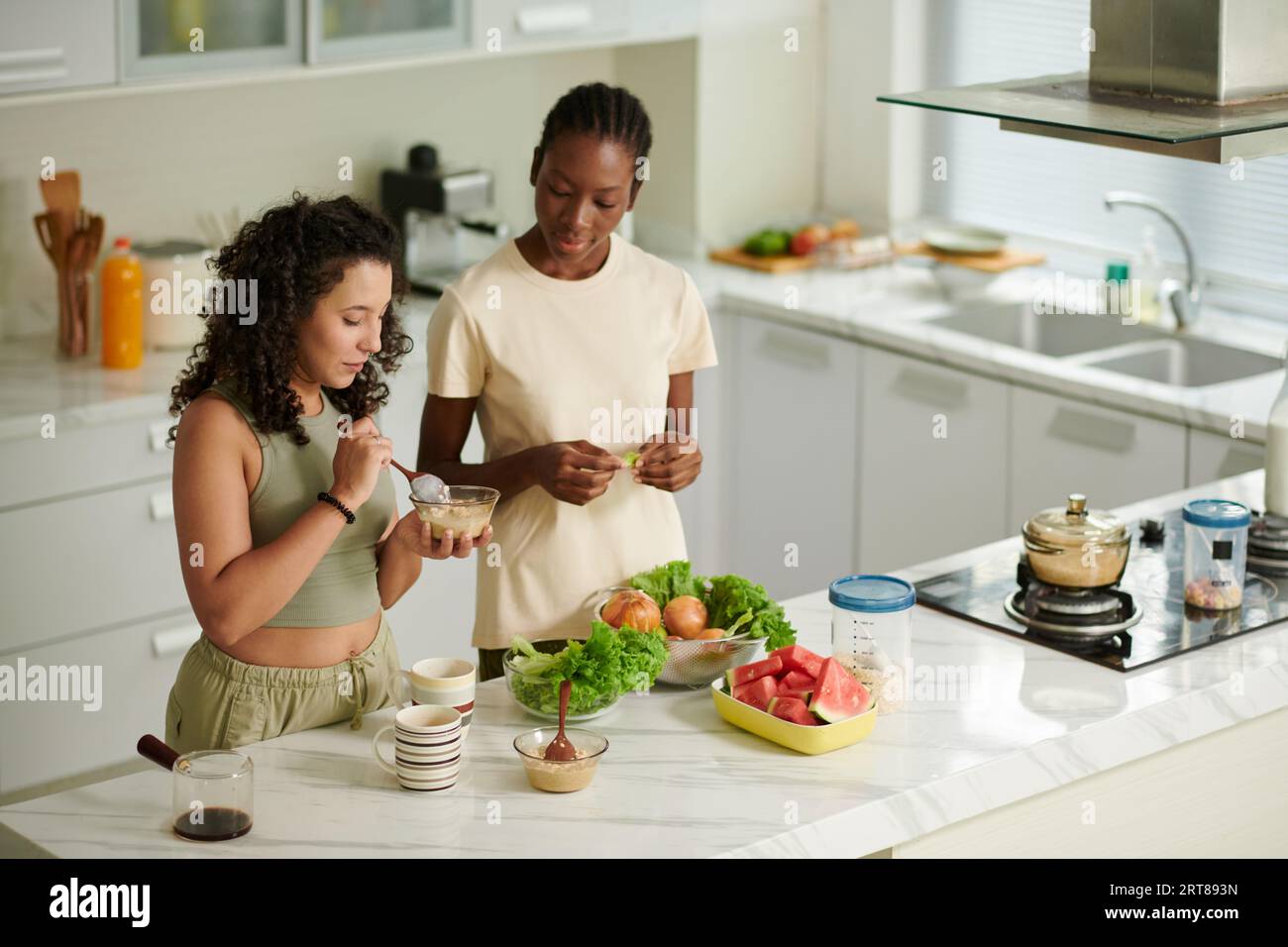 Young women eating oatmeal and fresh fruits and vegetables for ...