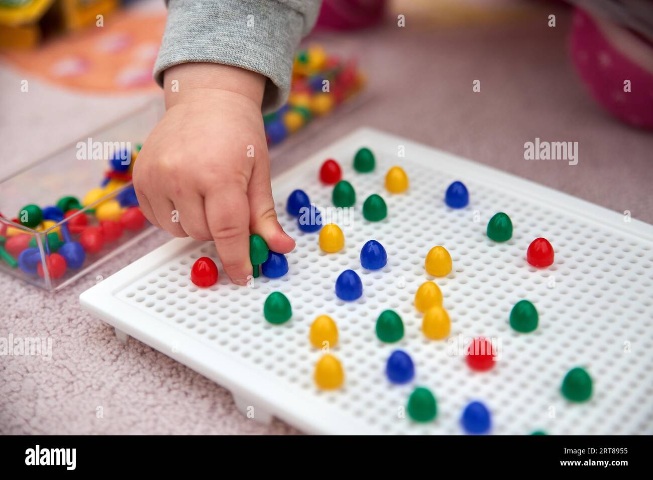 Toddler plays with colorful pins Stock Photo - Alamy