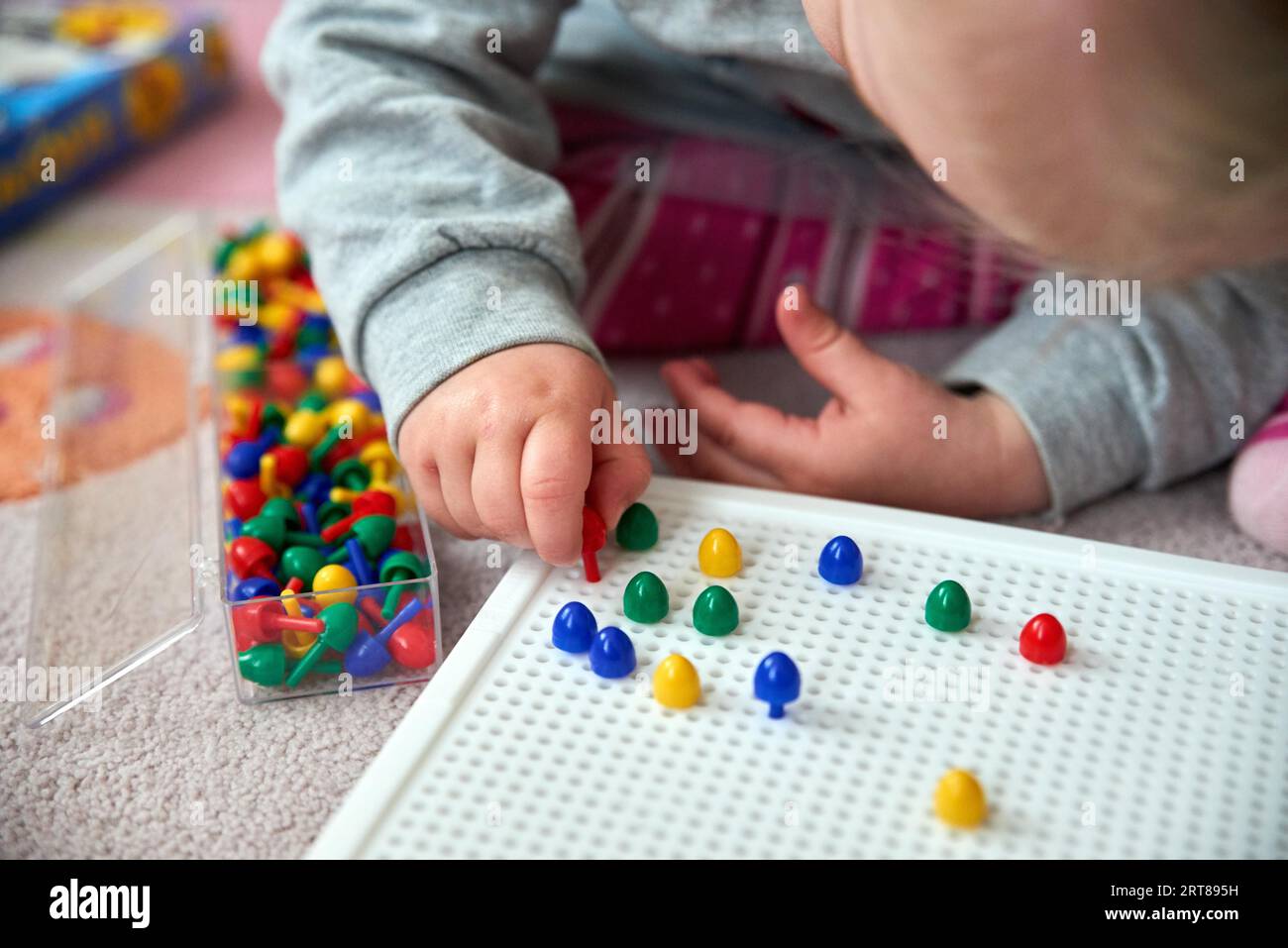 Toddler plays with colorful pins Stock Photo - Alamy