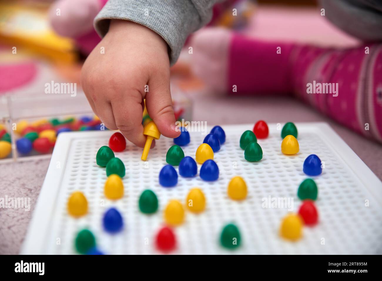 Toddler plays with colorful pins Stock Photo - Alamy