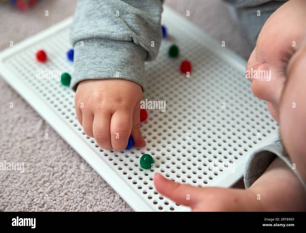 Toddler plays with colorful pins Stock Photo - Alamy