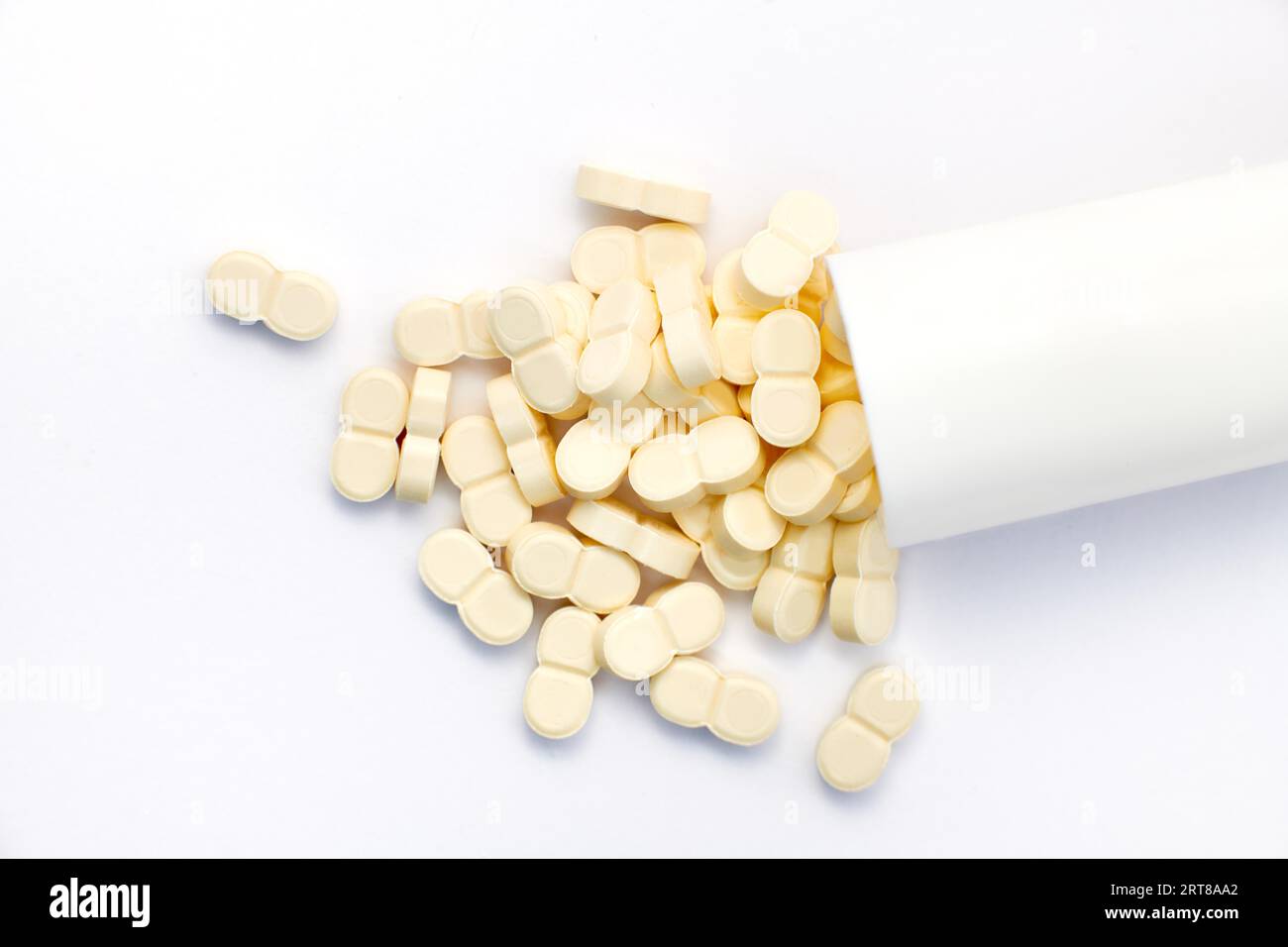 Pills coming out of bottle on white background Stock Photo - Alamy