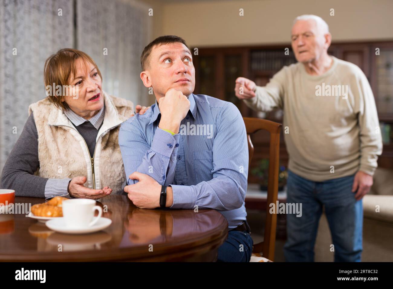 Mother calming adult son during quarrel with father Stock Photo - Alamy