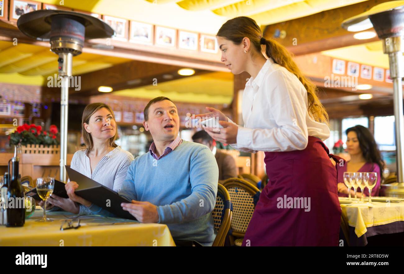Waitress recomending dishes to couple in restaurant Stock Photo - Alamy